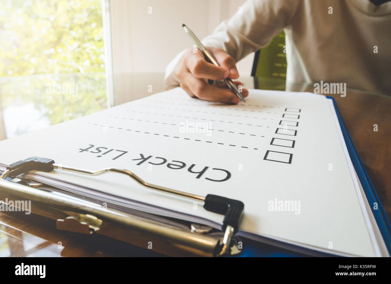 Close- up hand holding pen on check list paper And the format for ...