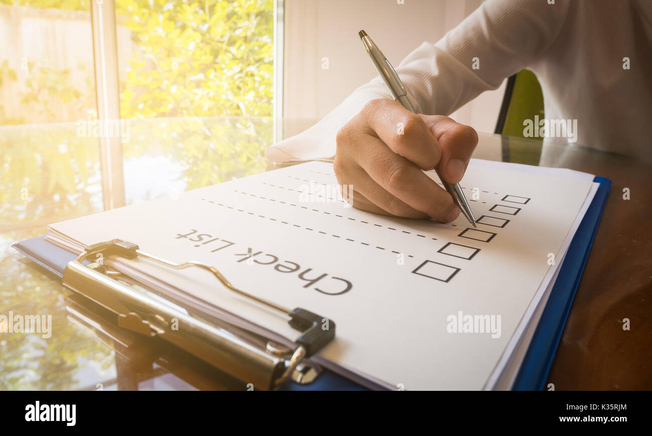 Close- up hand holding pen on check list paper and the format for ...