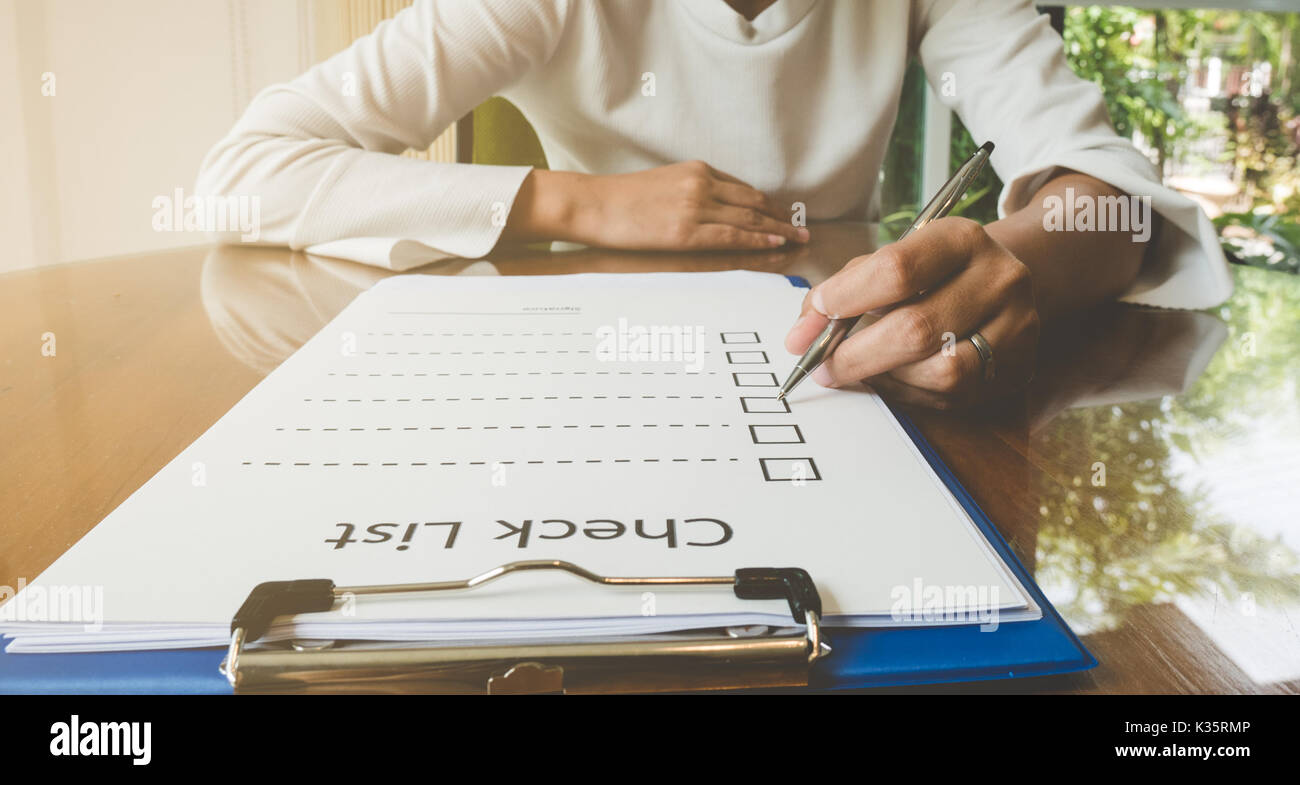Close- up hand holding pen on check list paper and the format for ...