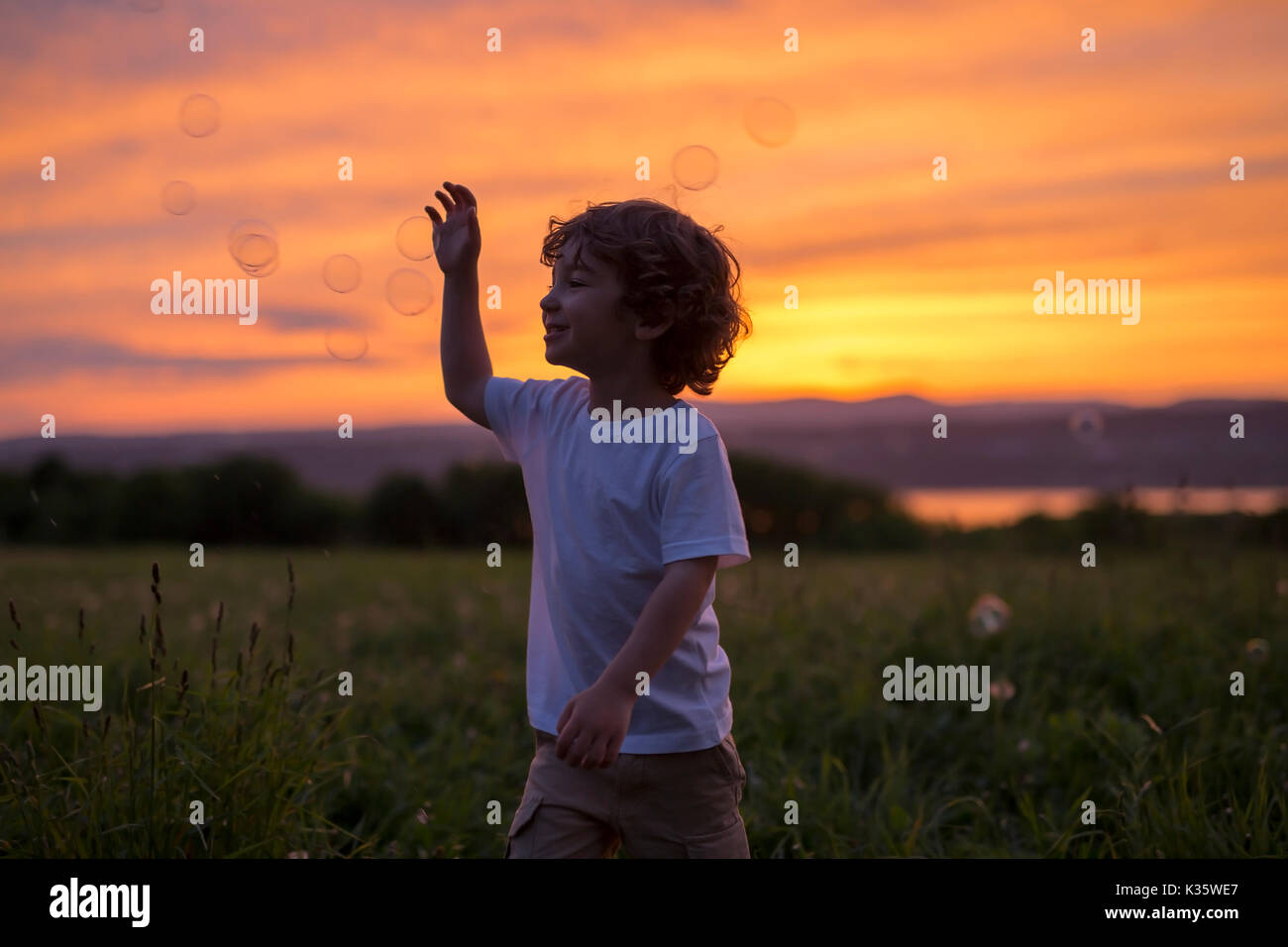 boy hit bubble on a sunset meadow Stock Photo - Alamy