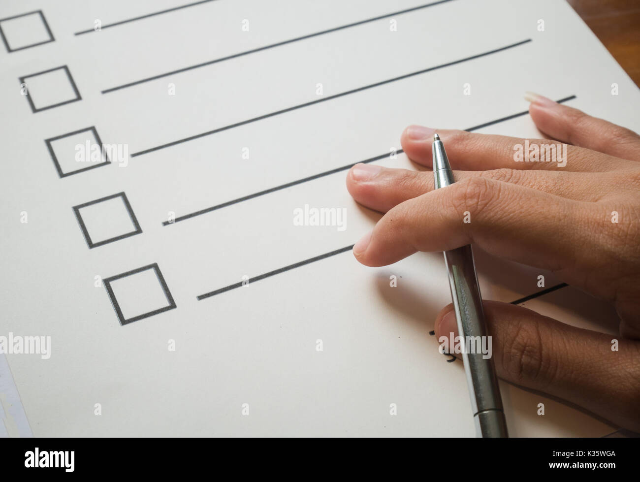 Close- up hand holding pen on check list paper and the format for ...