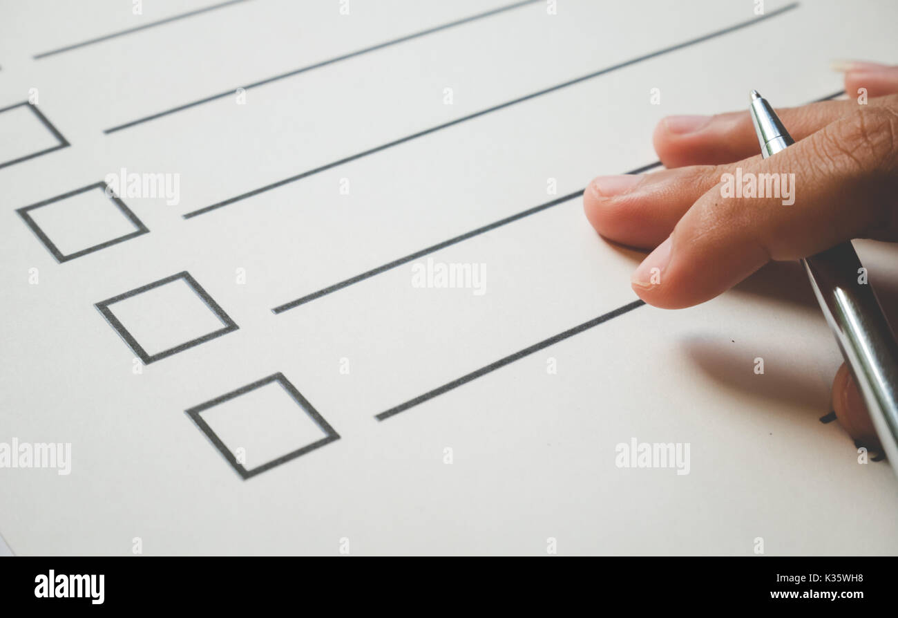 Close- up hand holding pen on check list paper and the format for ...