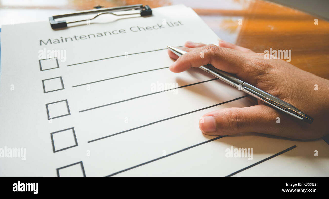 Close- up hand with pen on maintenance check paper and the format for ...