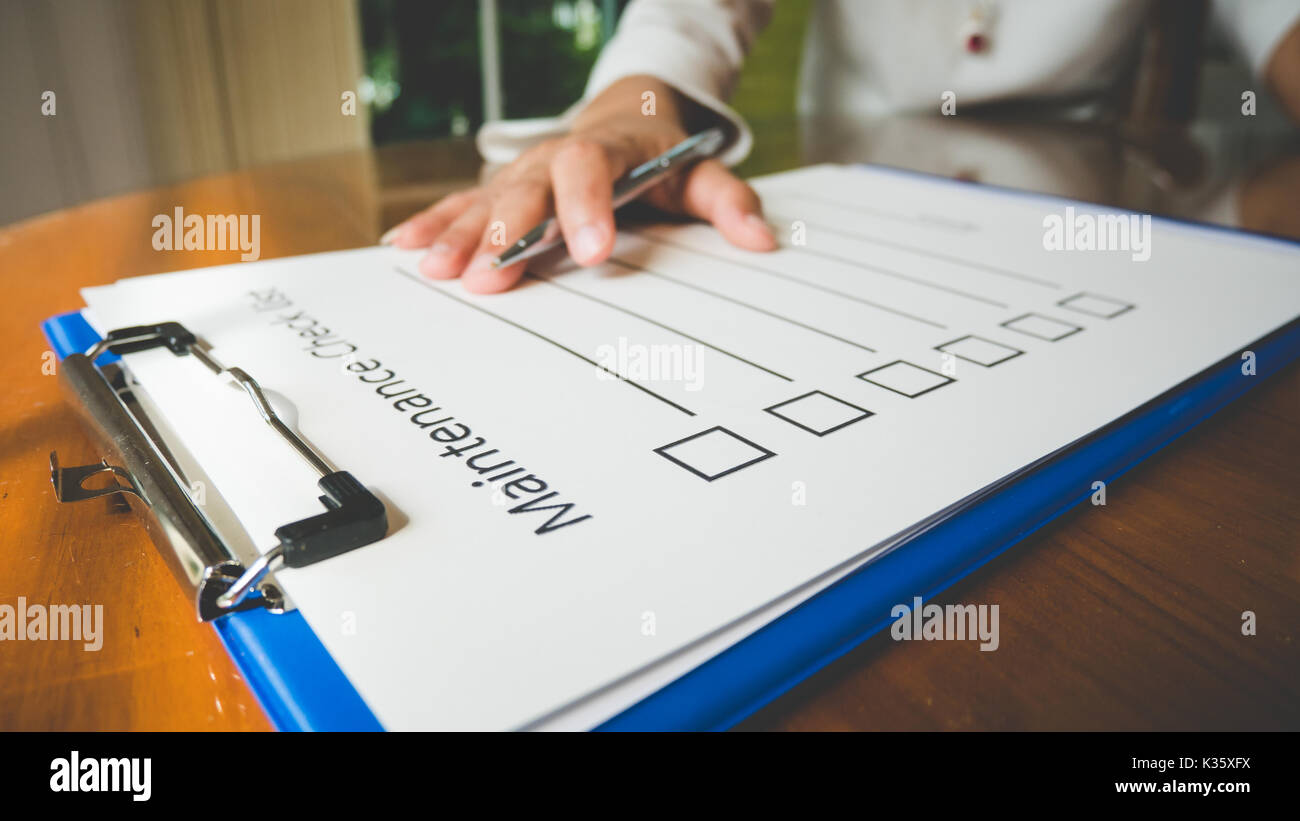 Close- up hand with pen on maintenance check paper and the format for ...
