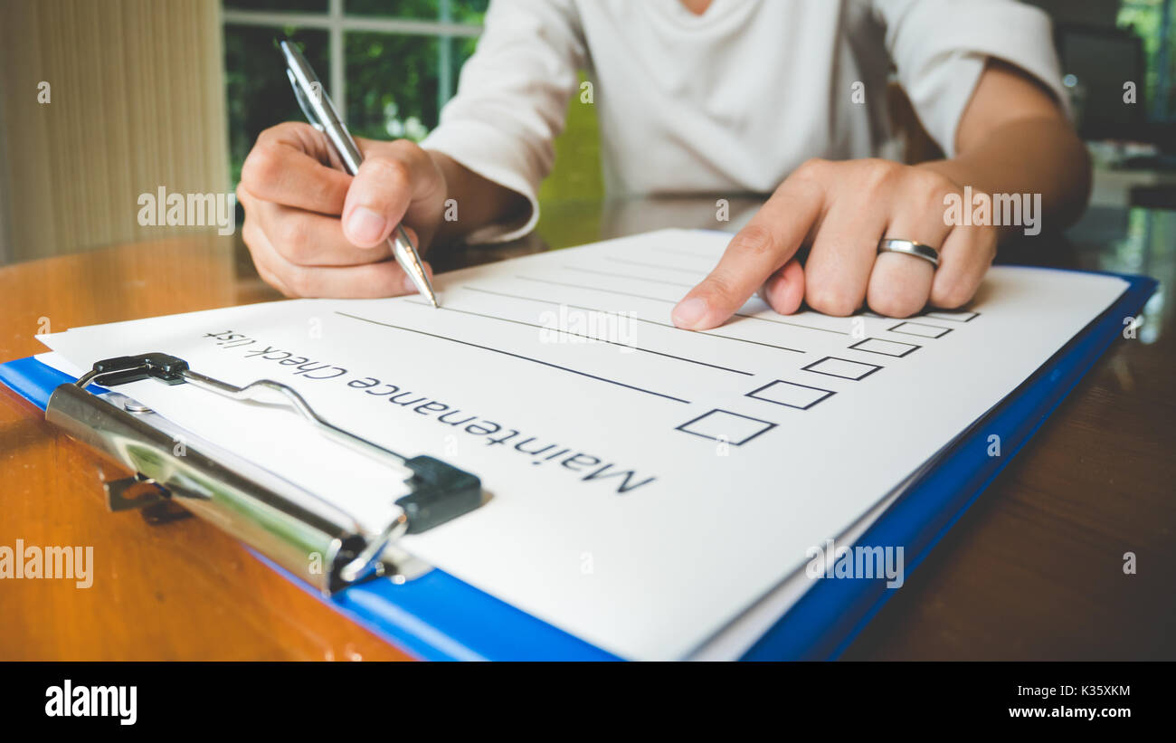 Close- up hand holding pen on maintenance check paper. hand point at ...
