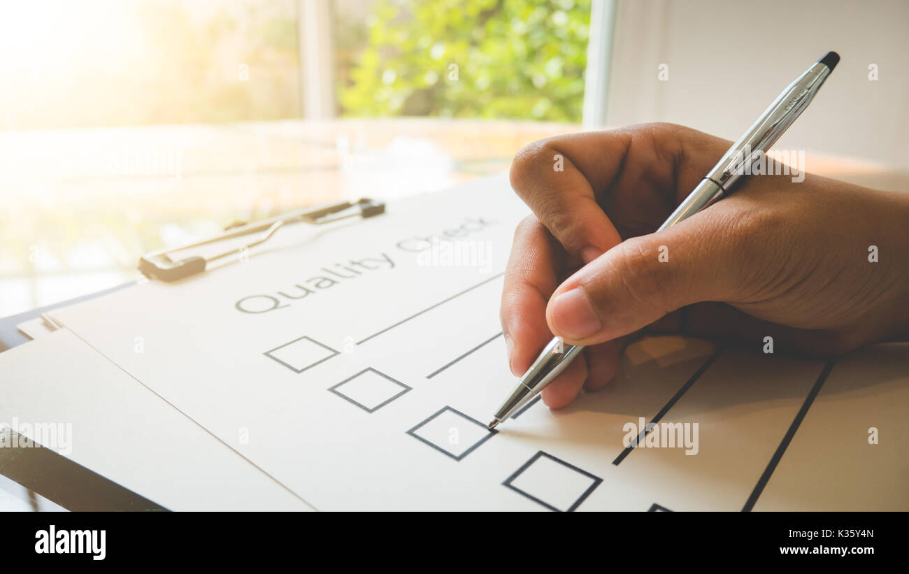 Close- up hand holding pen on quality check paper and the format for ...