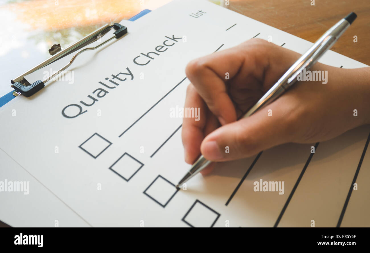 Close- up hand holding pen on quality check paper and the format for ...