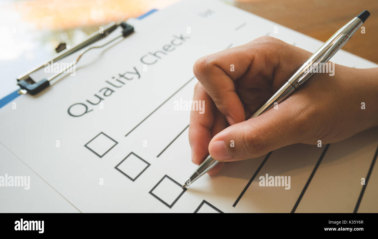 Close- up hand holding pen on quality check paper and the format for ...