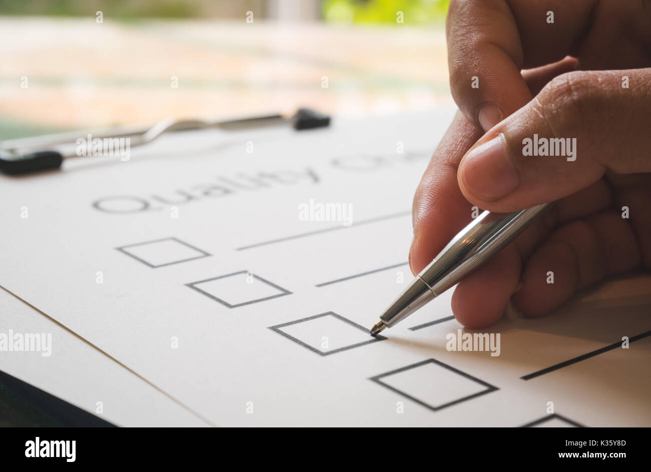 Close- up hand holding pen on quality check paper and the format for ...