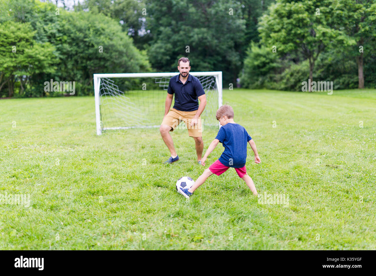father with son playing football on football pitch Stock Photo - Alamy