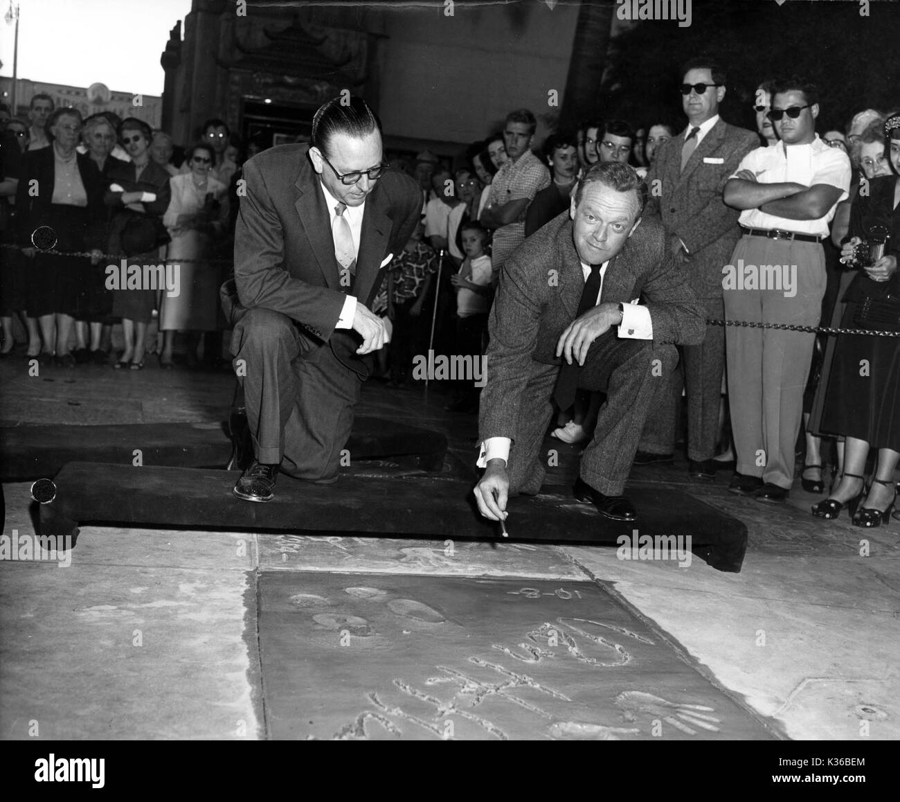 Van Johnson putting a date to his hand and footprints in wet concrete ...