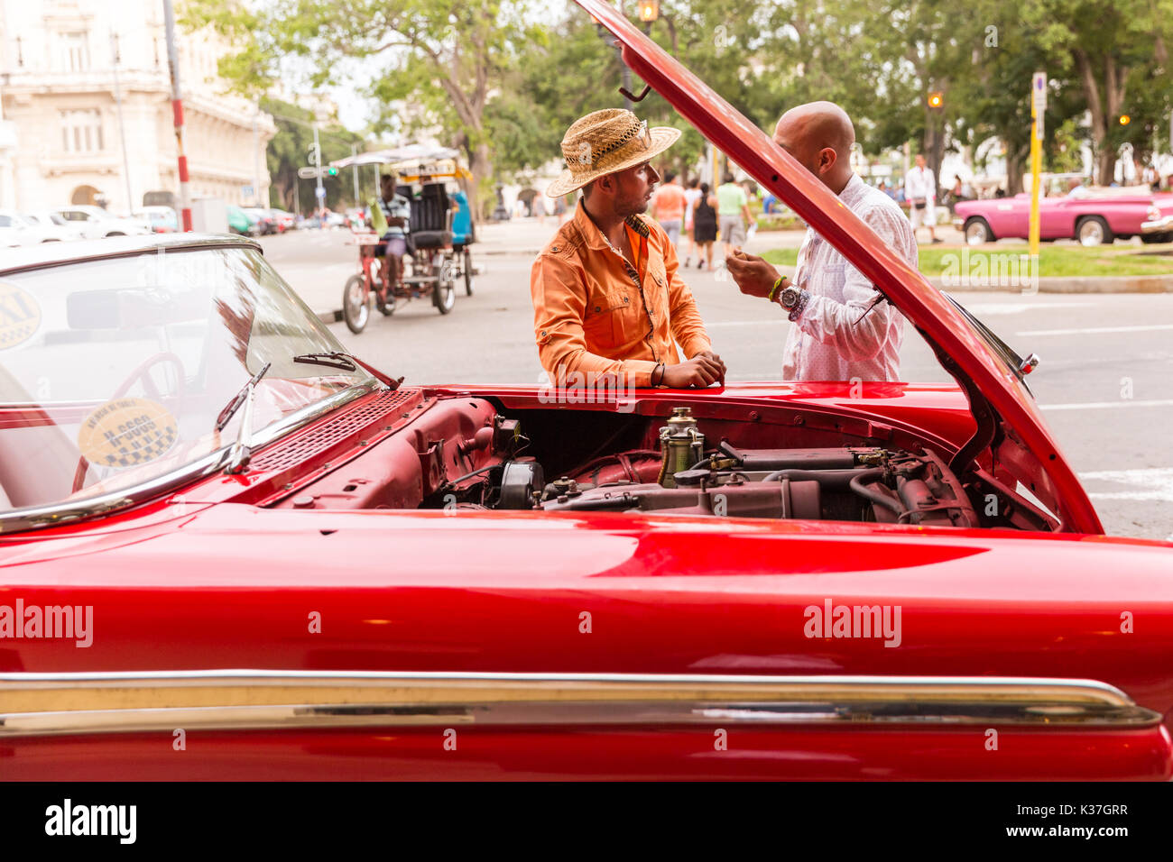 Havana taxi driver discusses repairs on his with red American classic ...