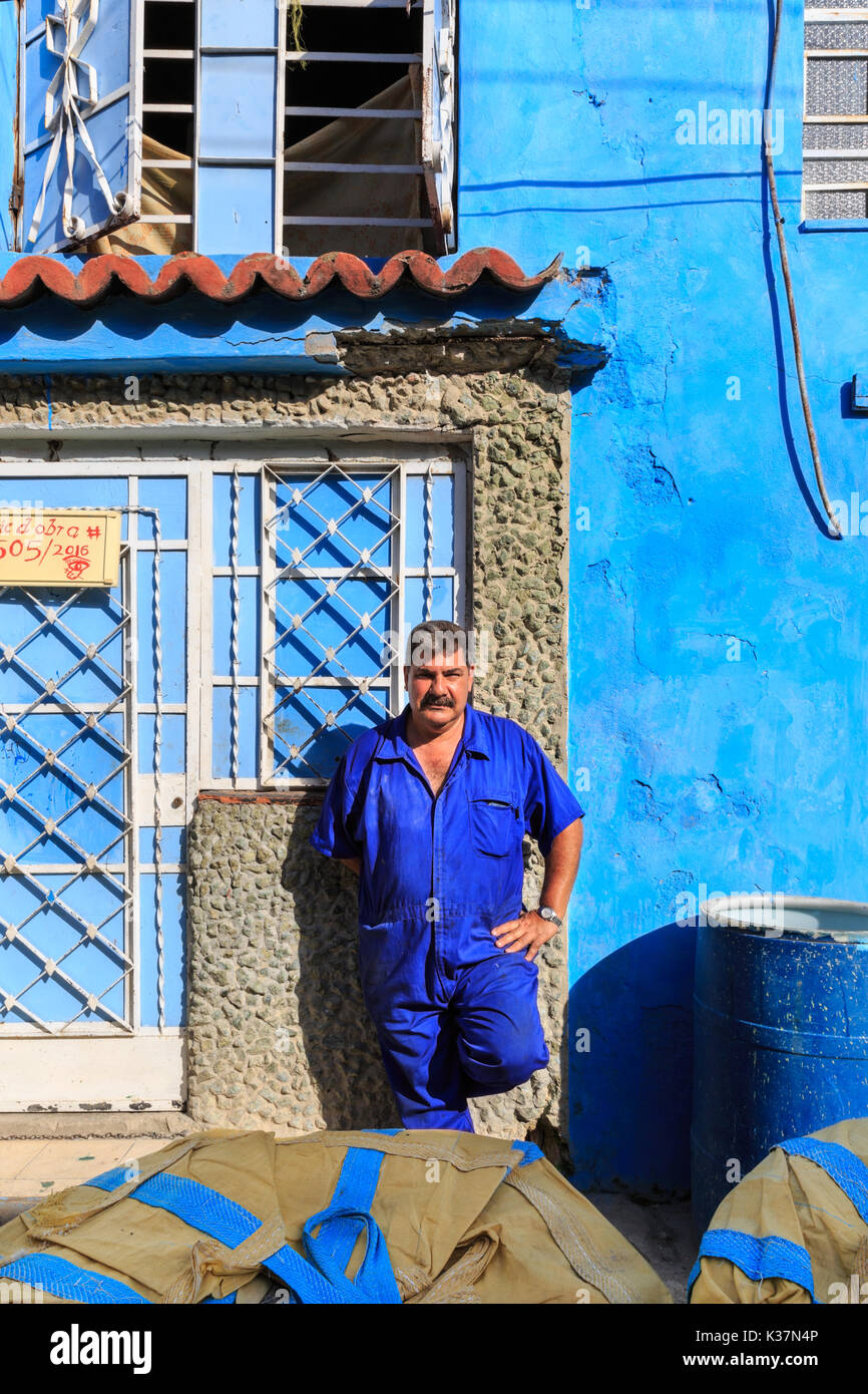 Cubal building worker poses in front of colourful residential houses ...