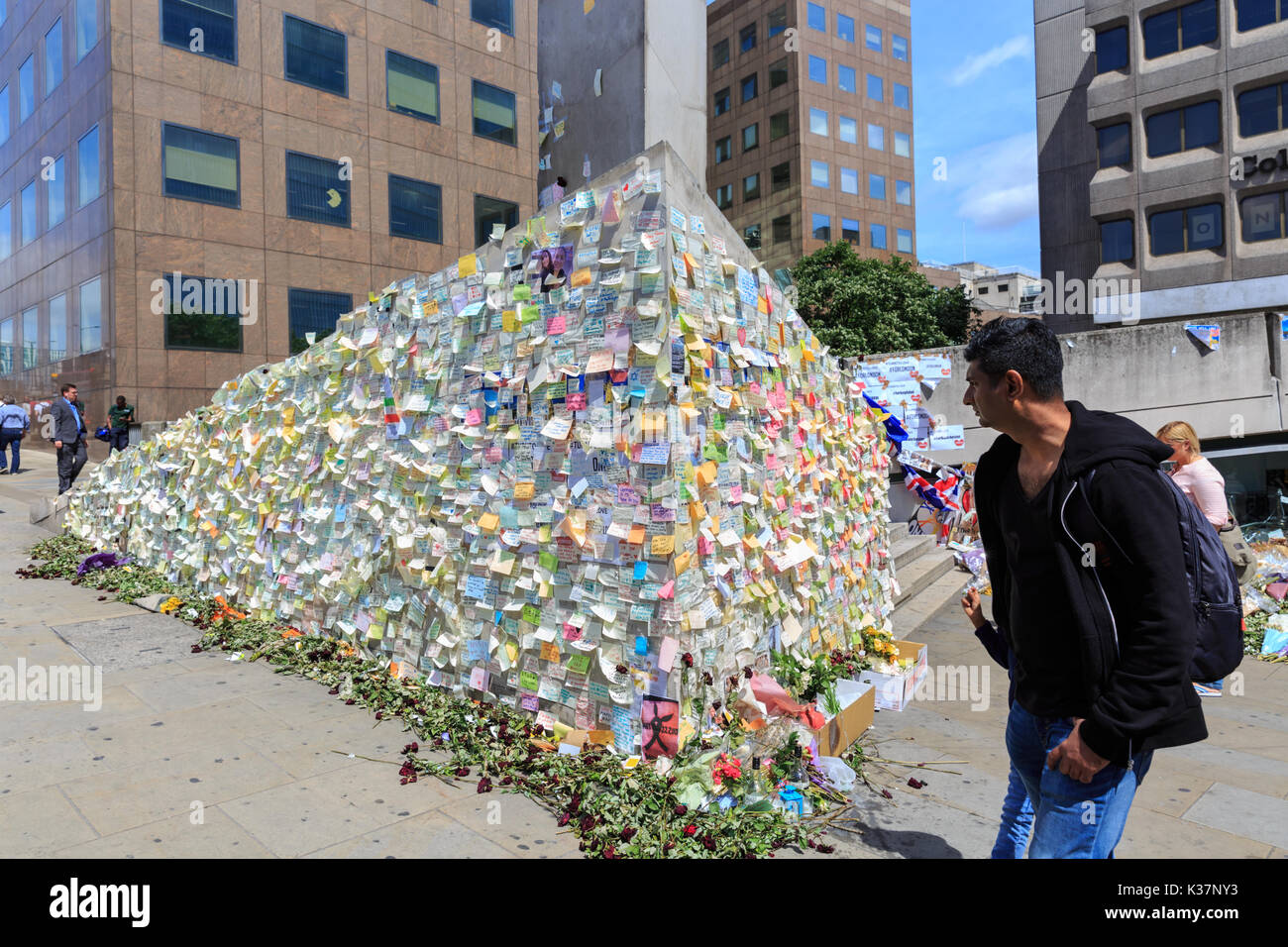 People look at wall of condolence cards, notes, tributes and flowers at ...