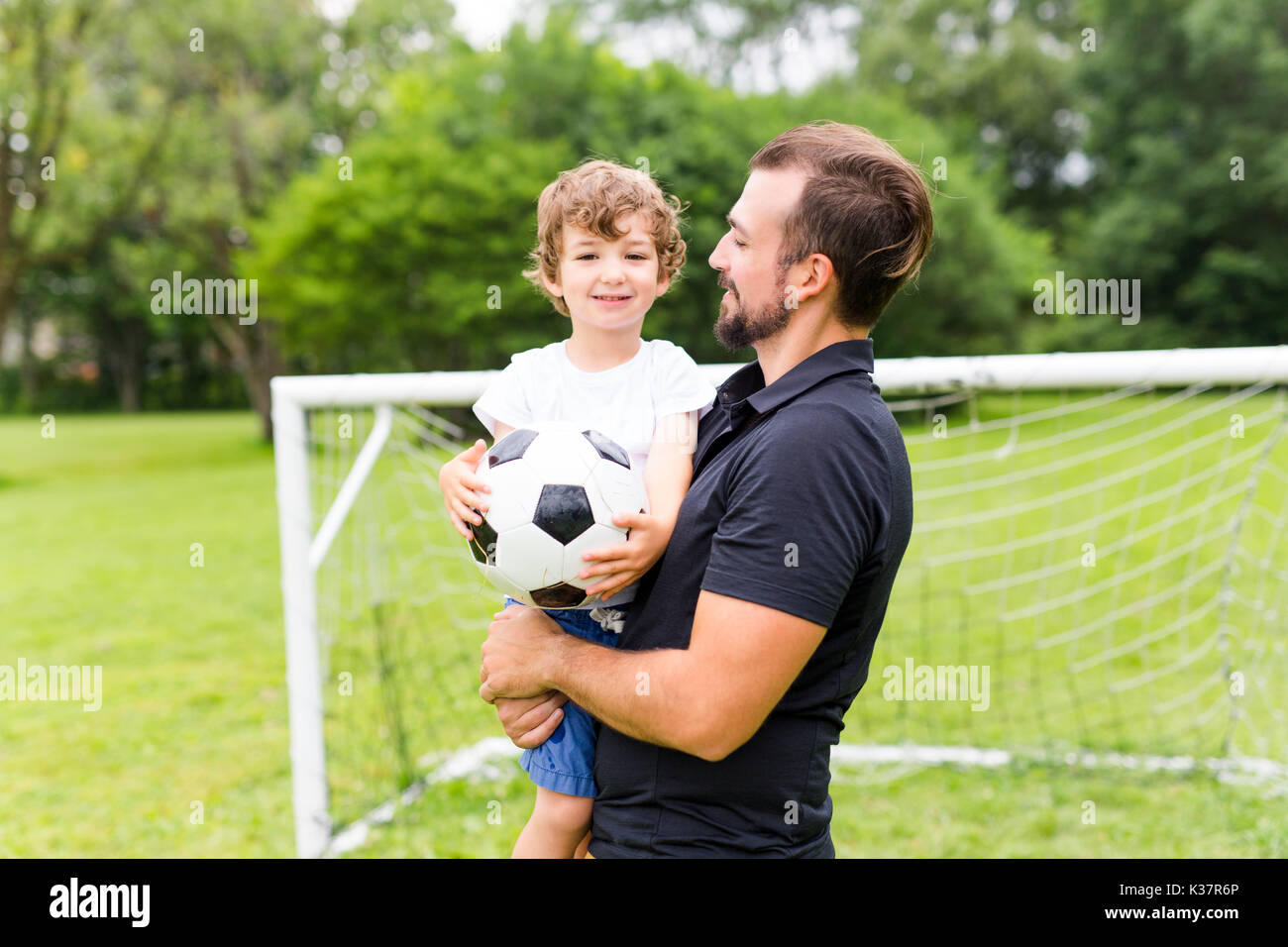 father with son playing football on football pitch Stock Photo - Alamy