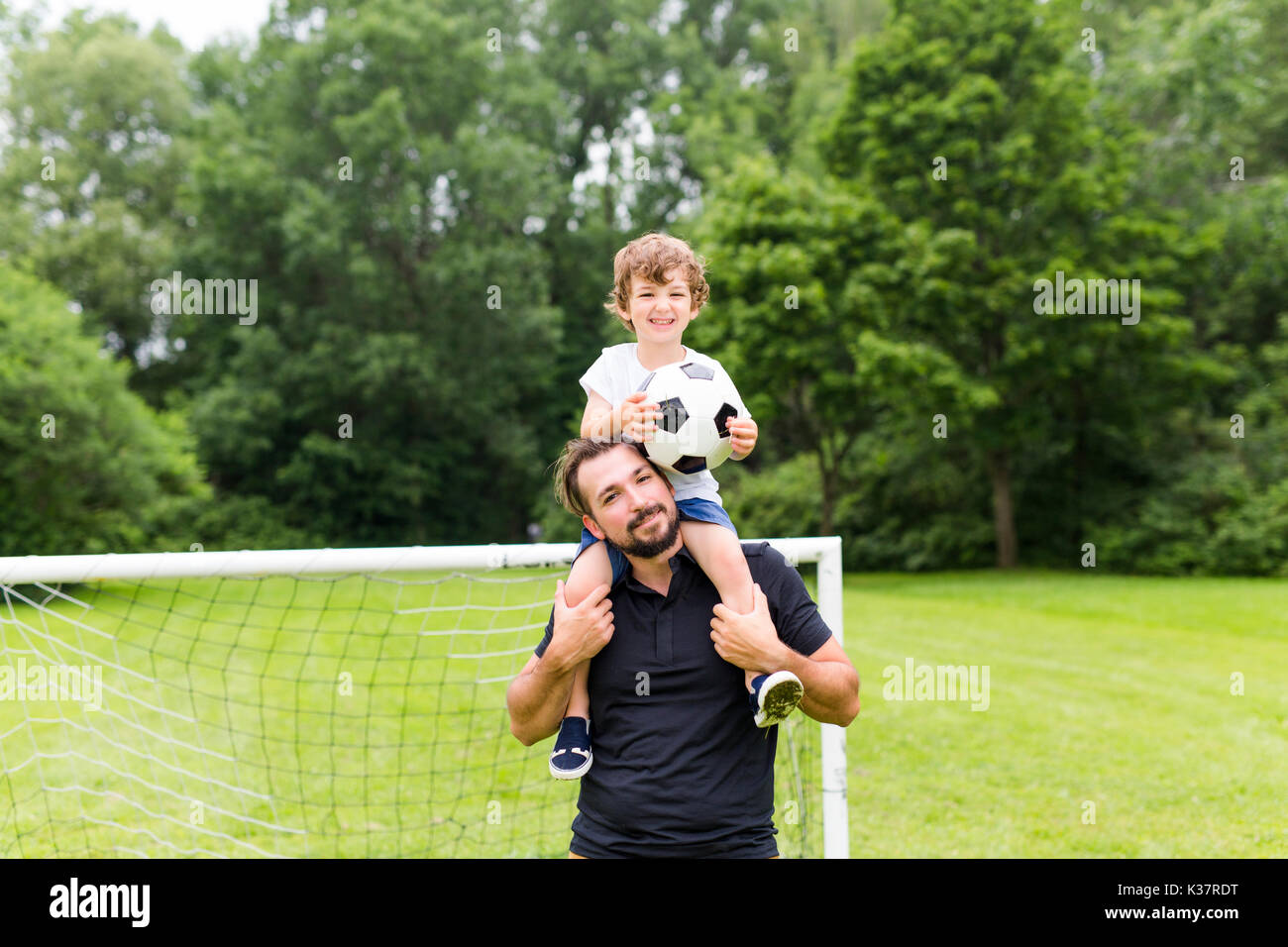 father with son playing football on football pitch Stock Photo - Alamy