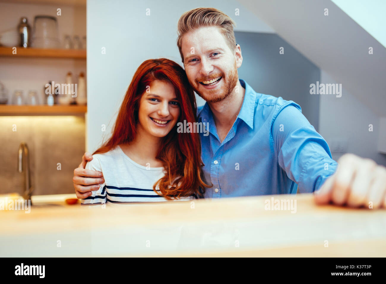 Happy couple in kitchen smiling Stock Photo - Alamy