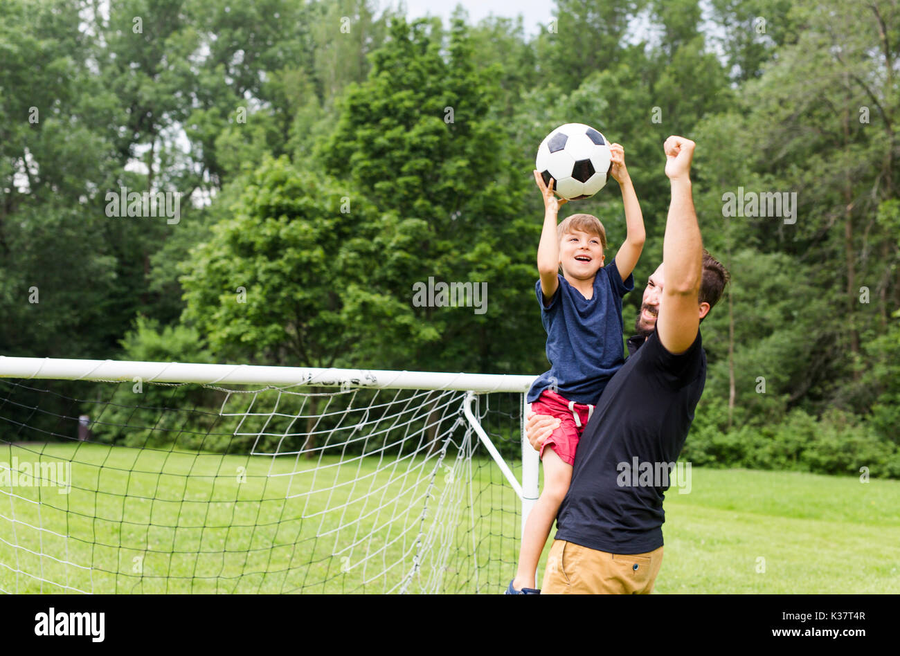 father with son playing football on football pitch Stock Photo - Alamy
