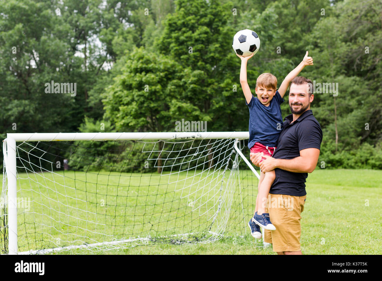 father with son playing football on football pitch Stock Photo - Alamy