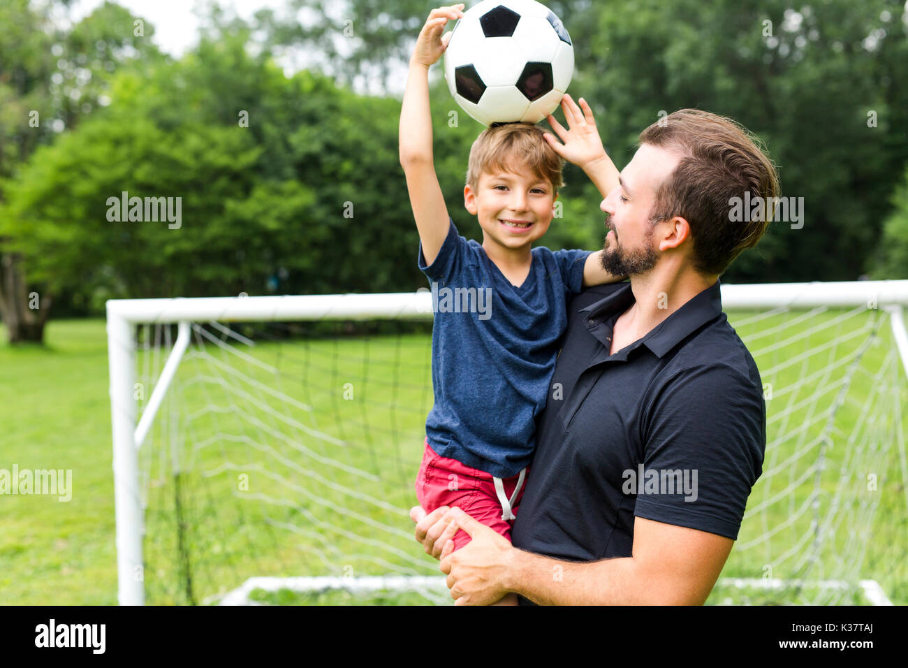 father with son playing football on football pitch Stock Photo - Alamy