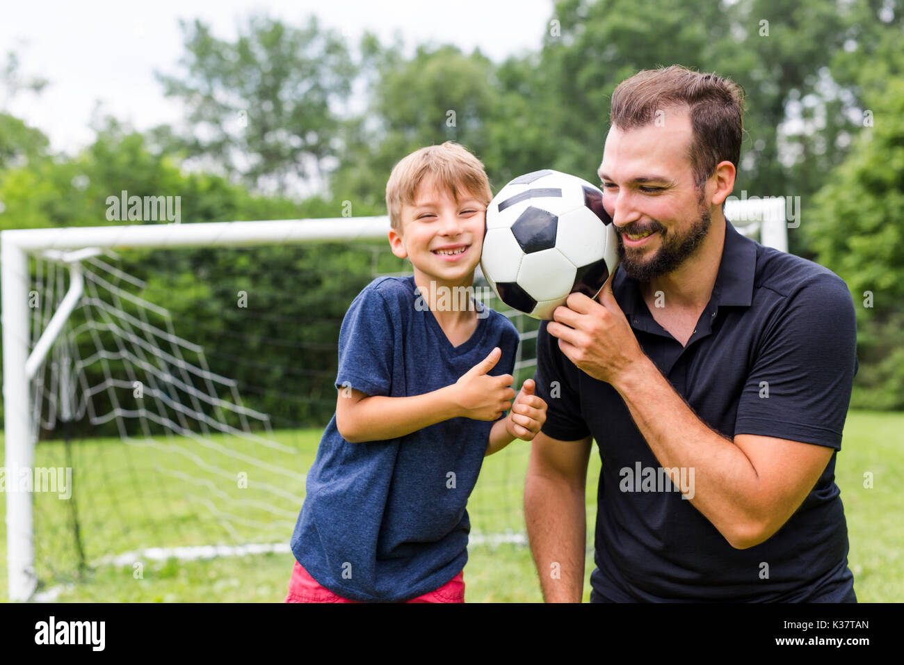 father with son playing football on football pitch Stock Photo - Alamy