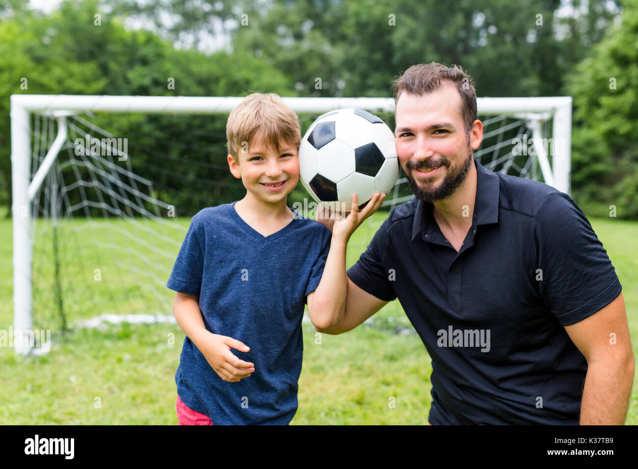 father with son playing football on football pitch Stock Photo - Alamy