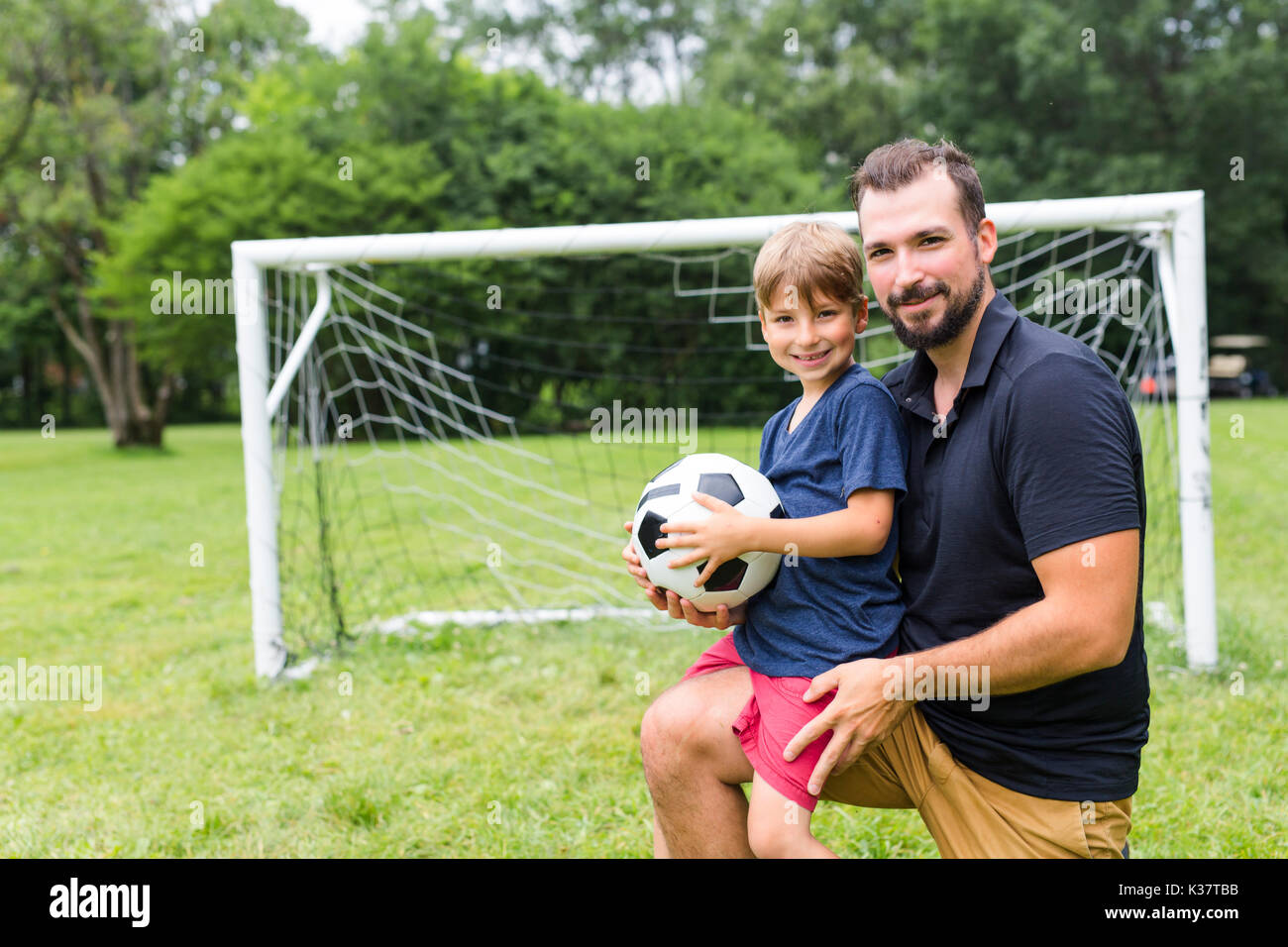 father with son playing football on football pitch Stock Photo - Alamy