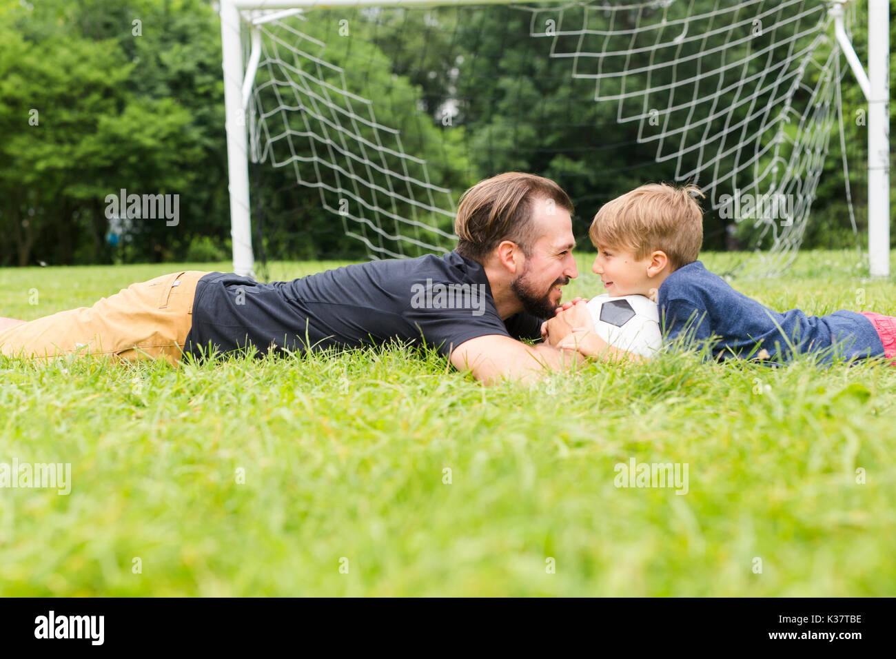 father with son playing football on football pitch Stock Photo - Alamy