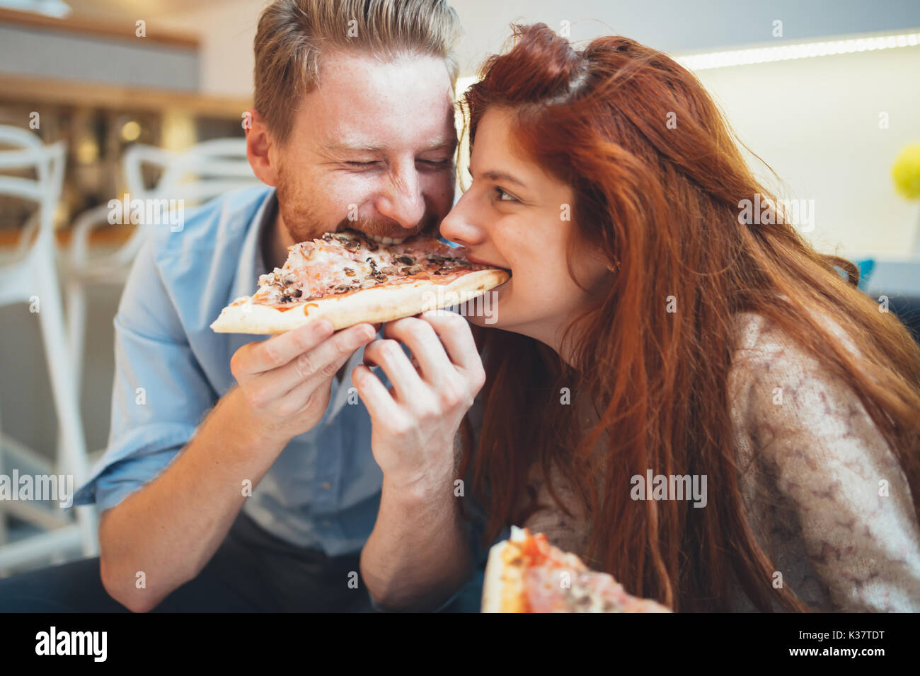 Couple sharing pizza and eating Stock Photo - Alamy
