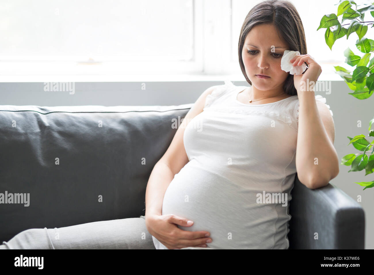 Sad pregnant woman lying on sofa at home Stock Photo - Alamy