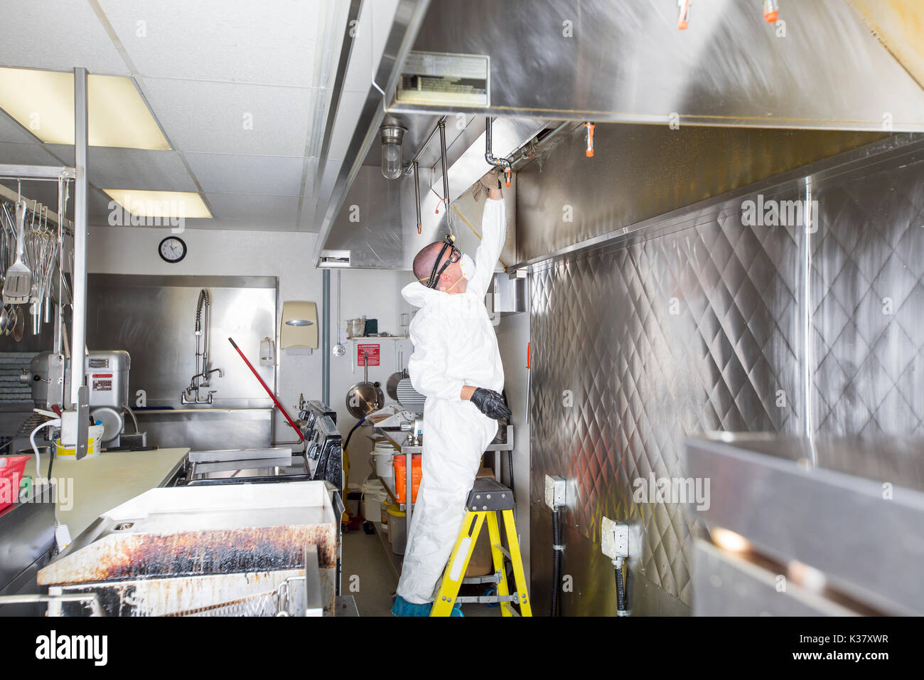 Commercial kitchen worker washing up at sink in professional kitchen ...