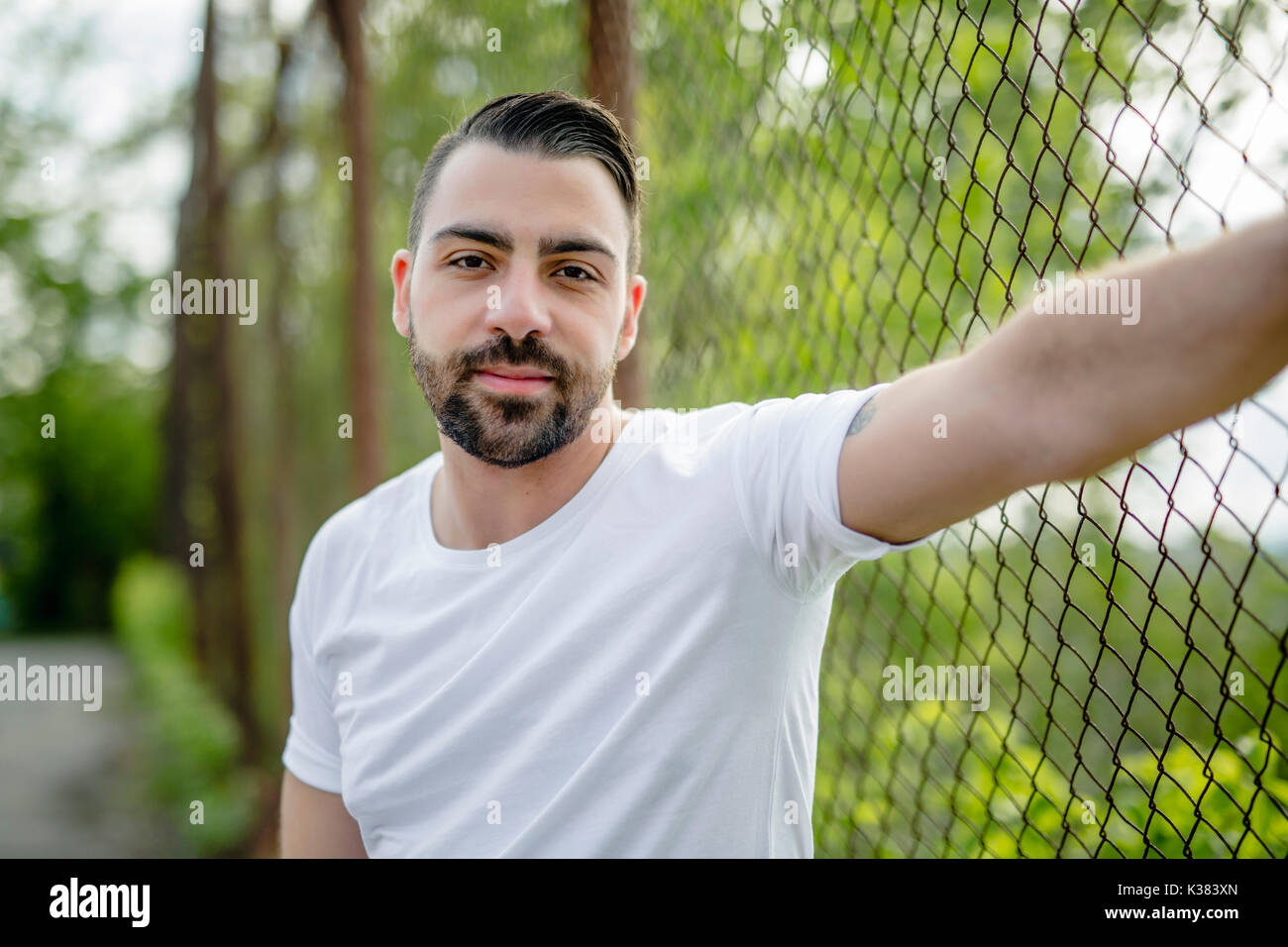 pretty men standing near chain link fence Stock Photo - Alamy