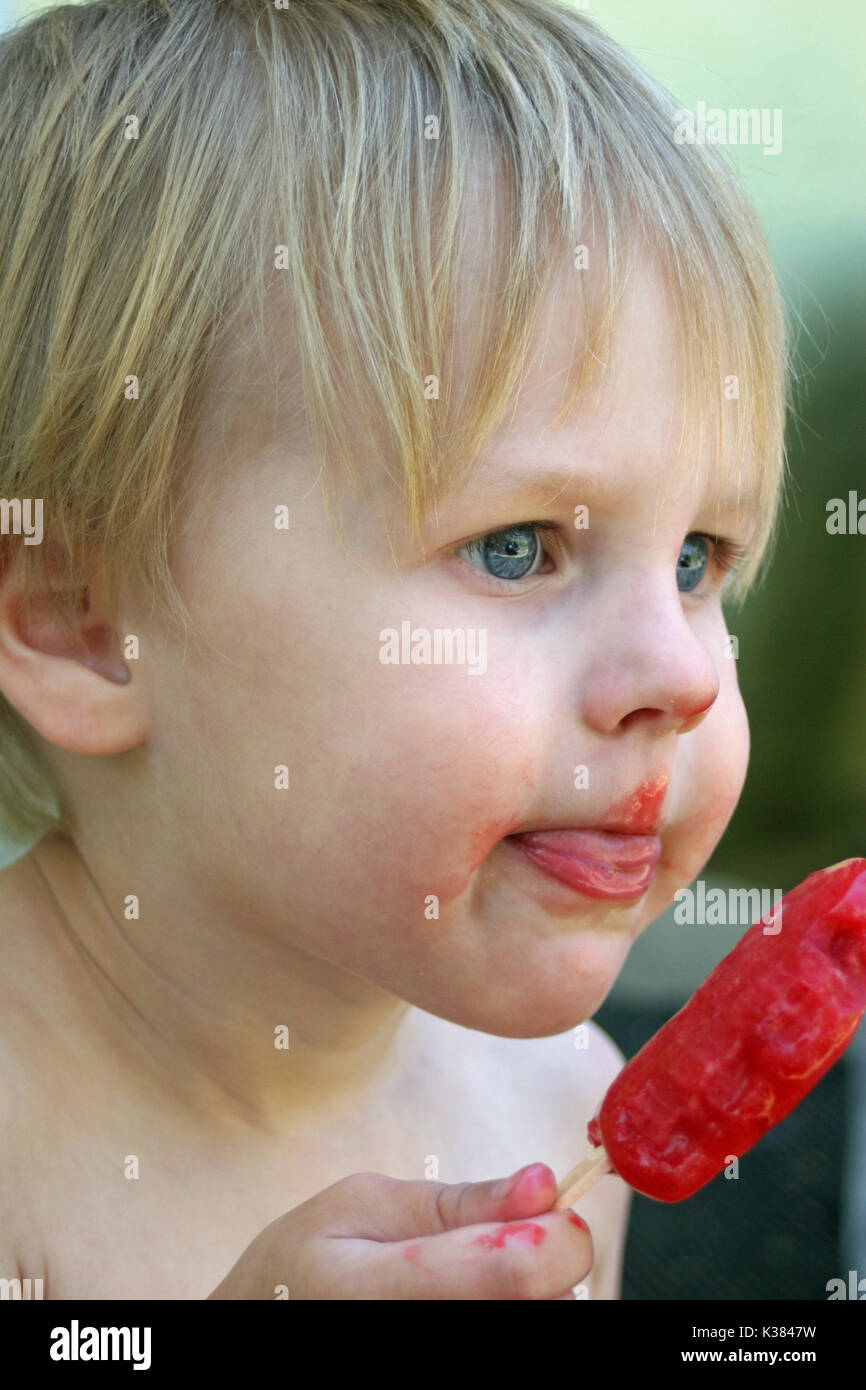 YOUNG BOY EATING RED POPSICLE Stock Photo - Alamy