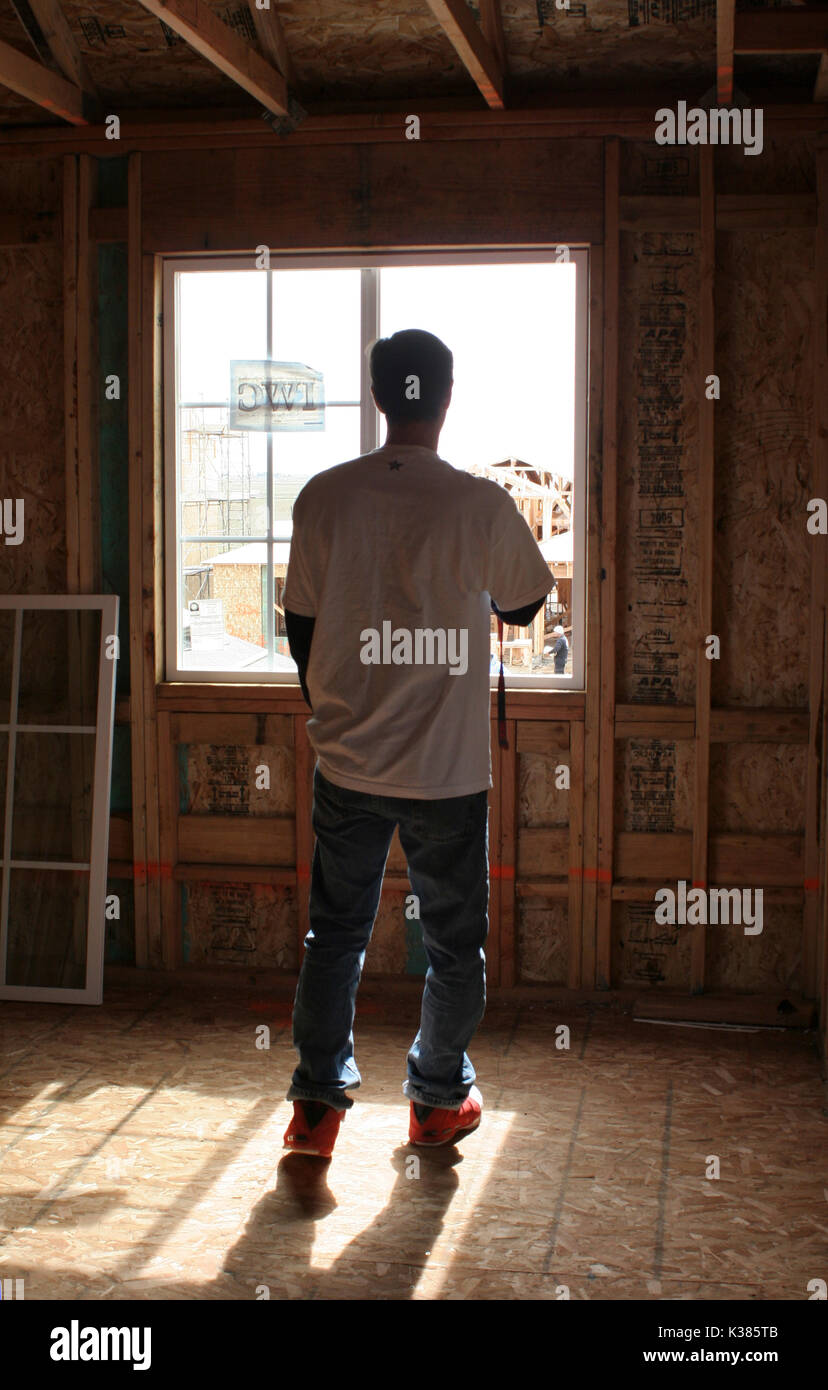 MAN LOOKING OUT WINDOW OF HOUSE UNDER CONSTRUCTION Stock Photo - Alamy