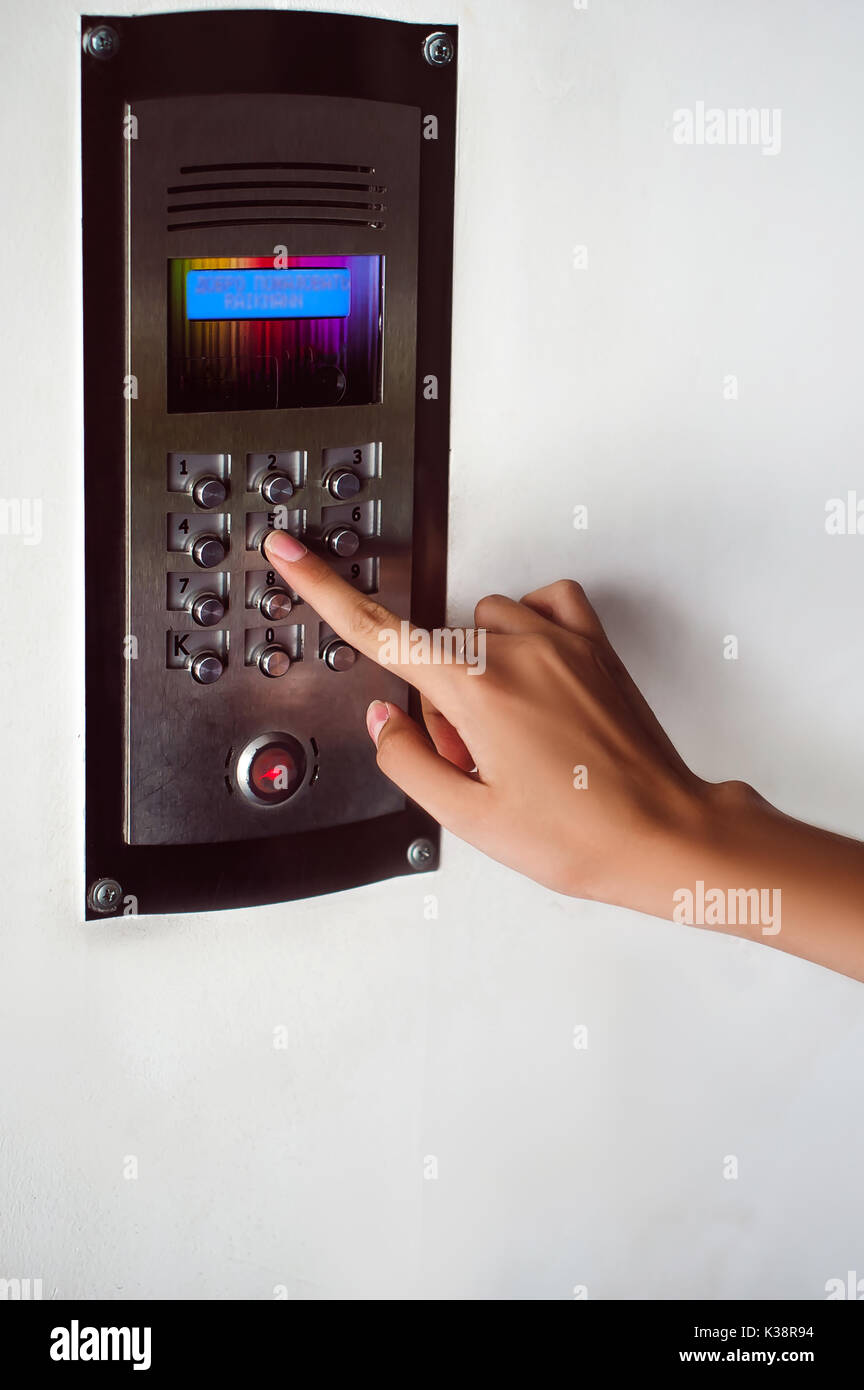 attractive woman in a blue elegant dress, dials code into intercom, at ...