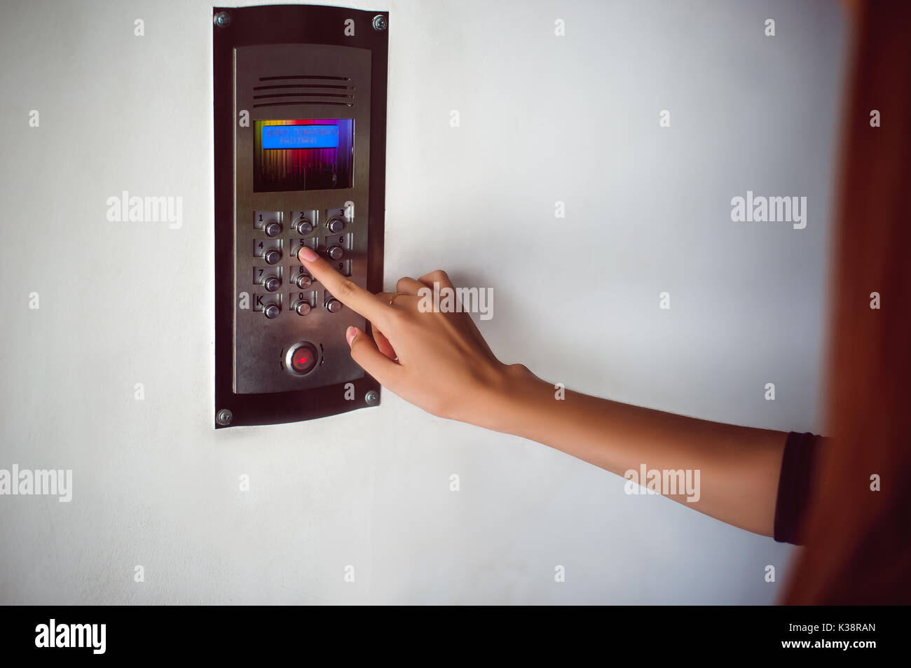 attractive woman in a blue elegant dress, dials code into intercom, at ...
