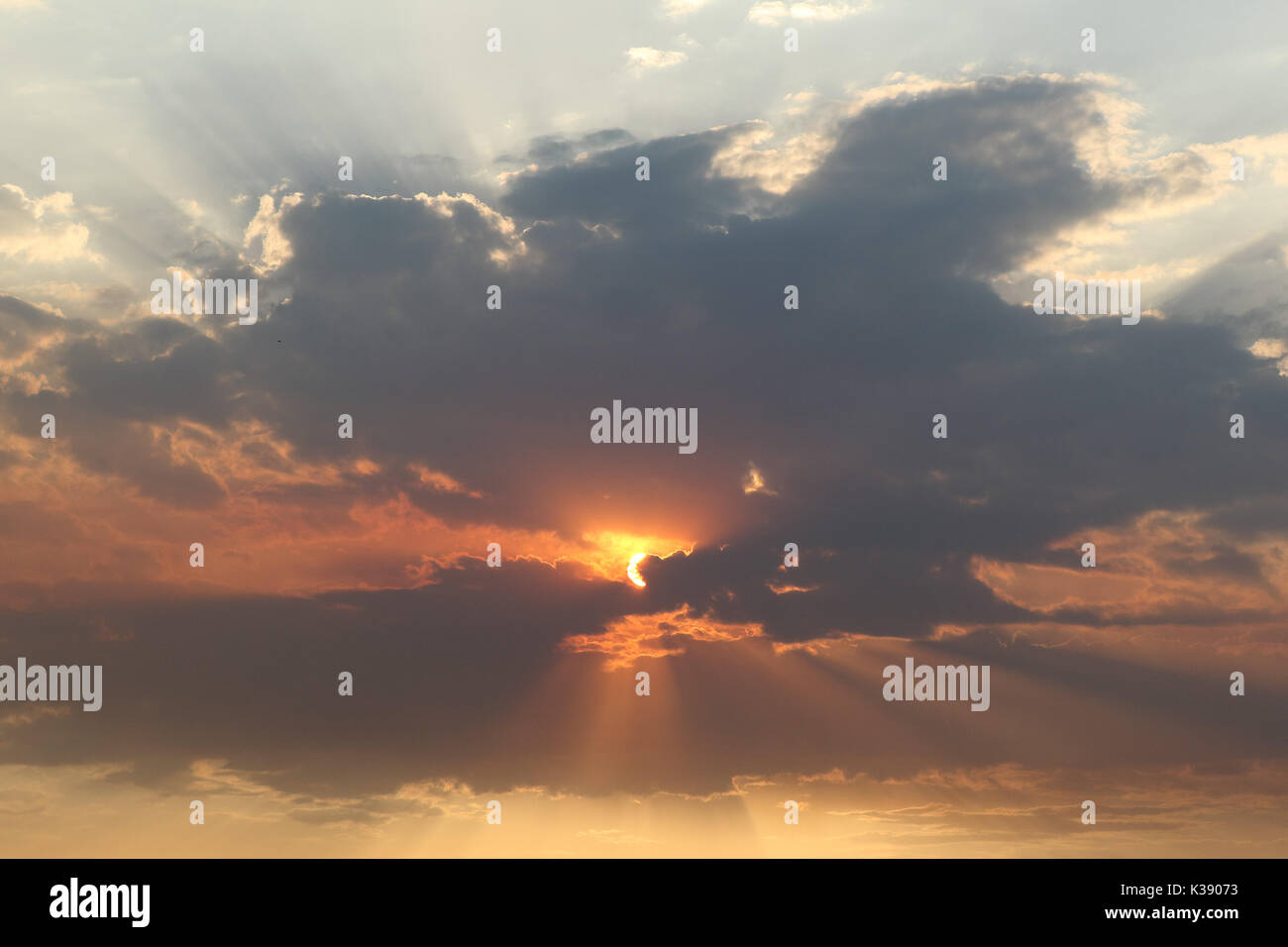 Evening sun behind clouds with sun rays Stock Photo - Alamy
