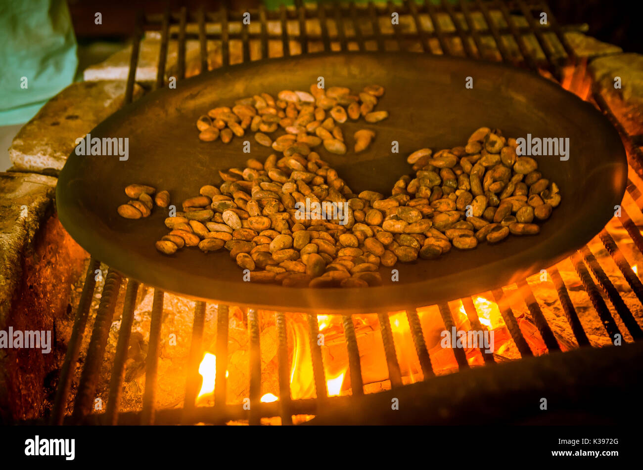 Close up of cacao bean inside of a metallic tray, over a wood stove ...