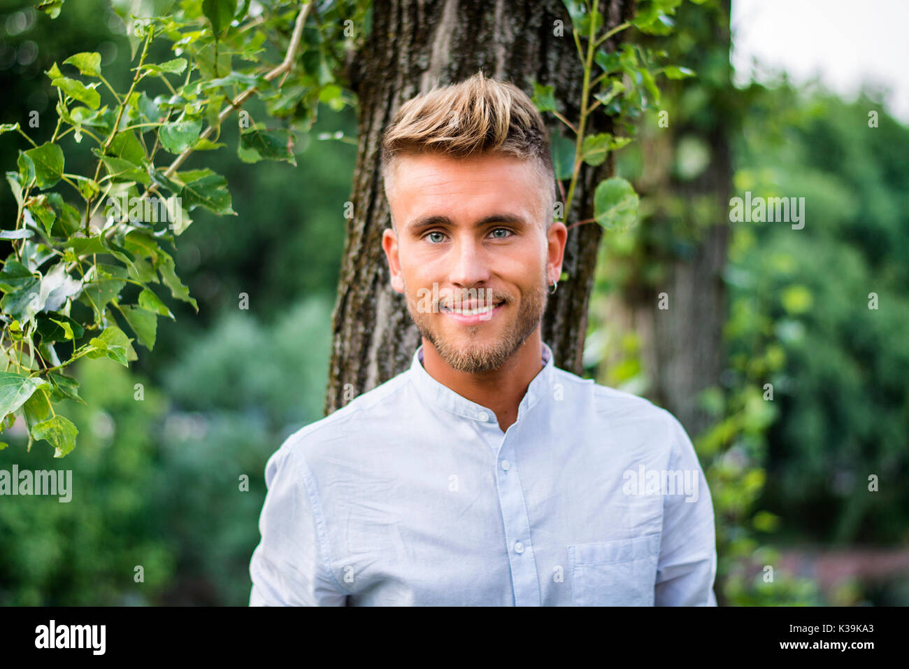 Handsome young man leaning against tree hi-res stock photography and ...