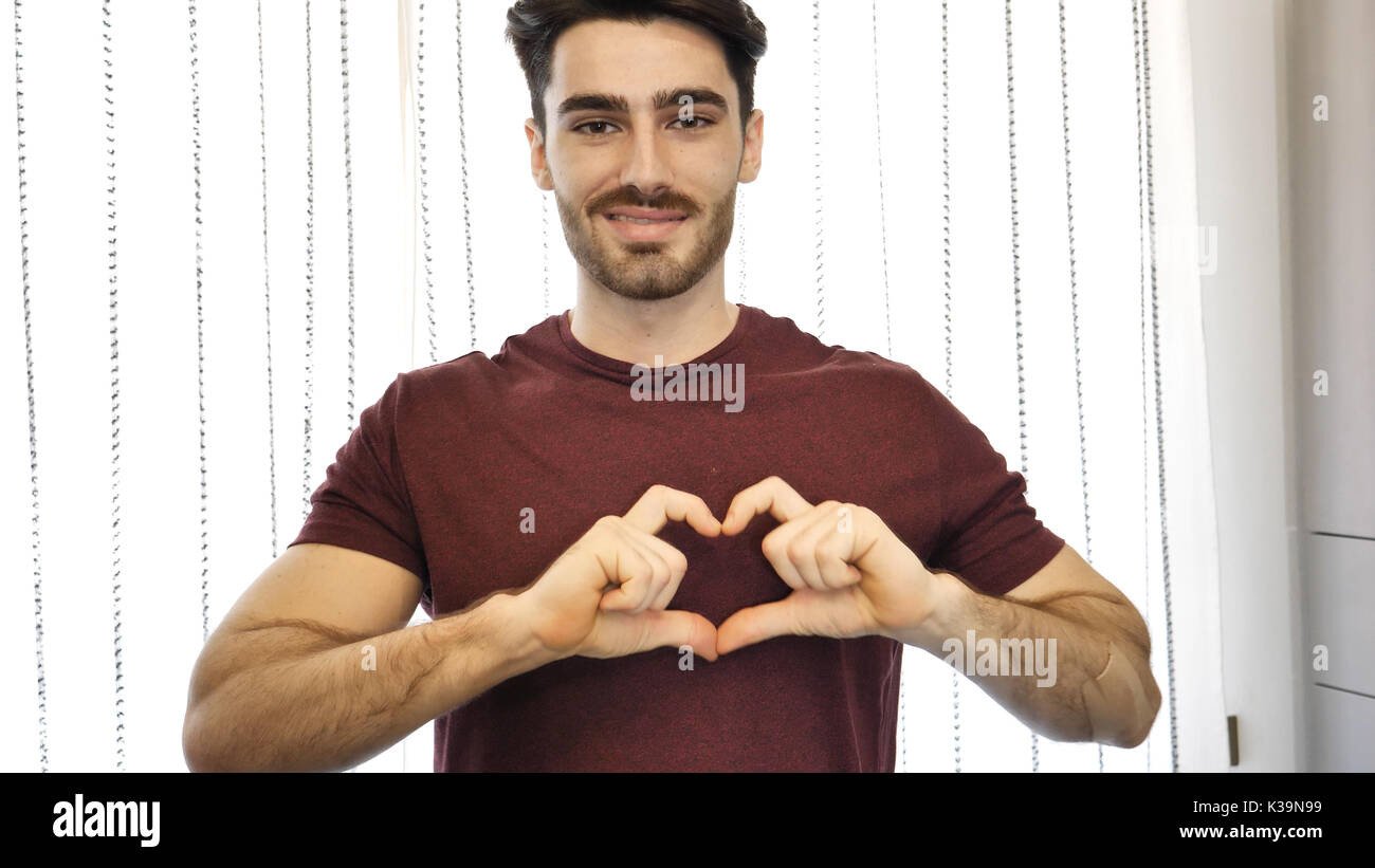 Handsome young man making heart sign with hands Stock Photo - Alamy