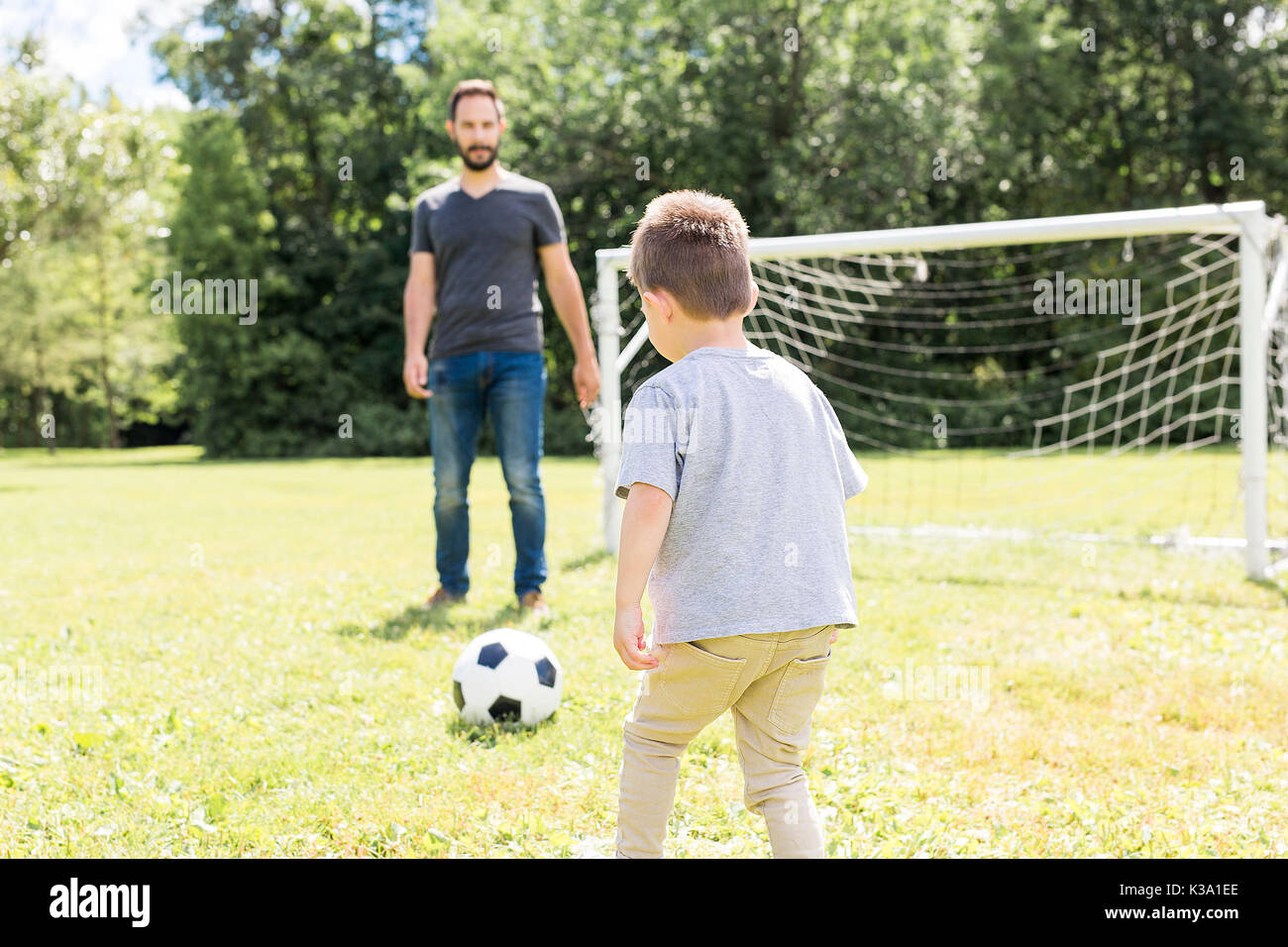 Young father with his little son playing football on football pitch ...