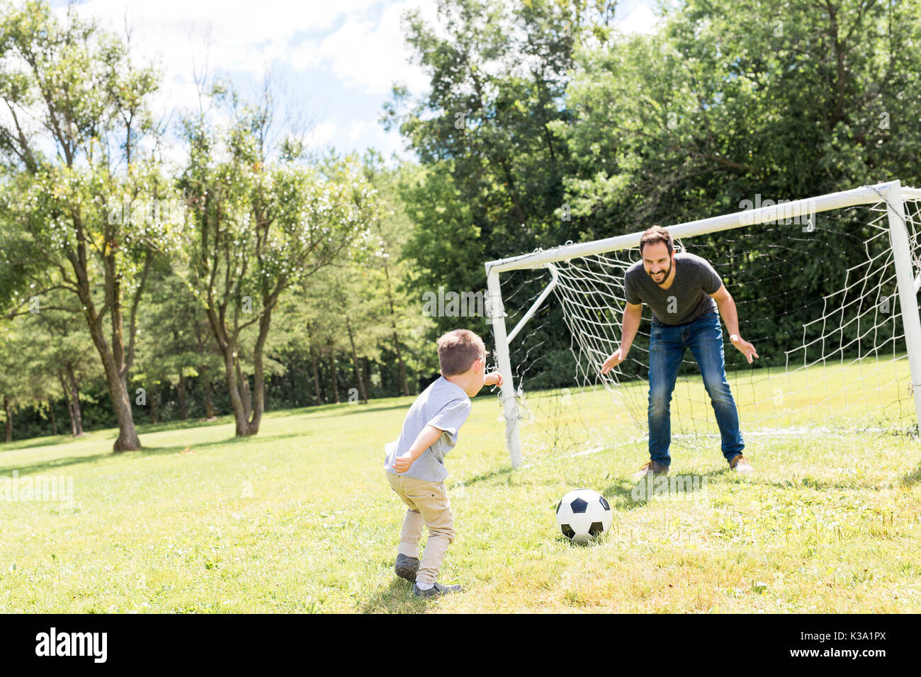 Young father with his little son playing football on football pitch ...