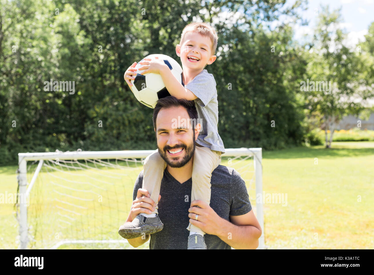 Young father with his little son playing football on football pitch ...