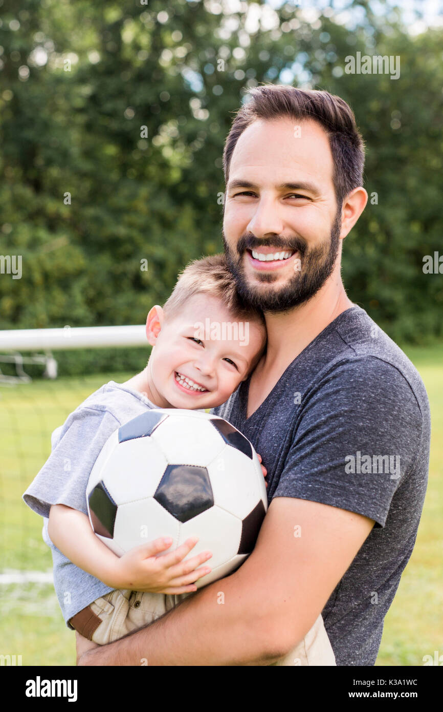 Young father with his little son playing football on football pitch ...