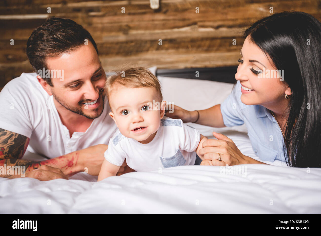 Loving parents with their cute little boy on bed Stock Photo - Alamy