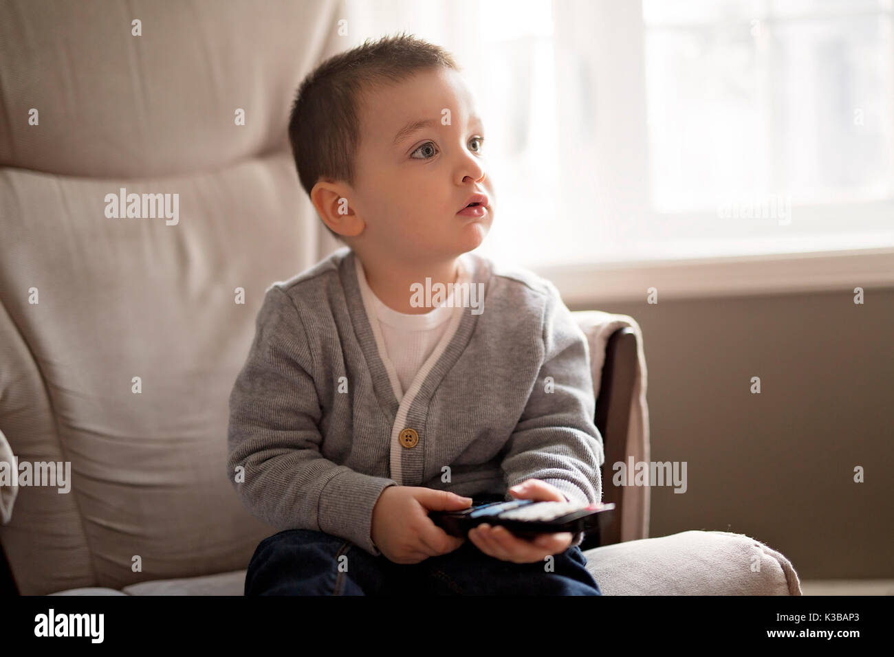 Little boy is watching tv while sitting on a couch Stock Photo - Alamy