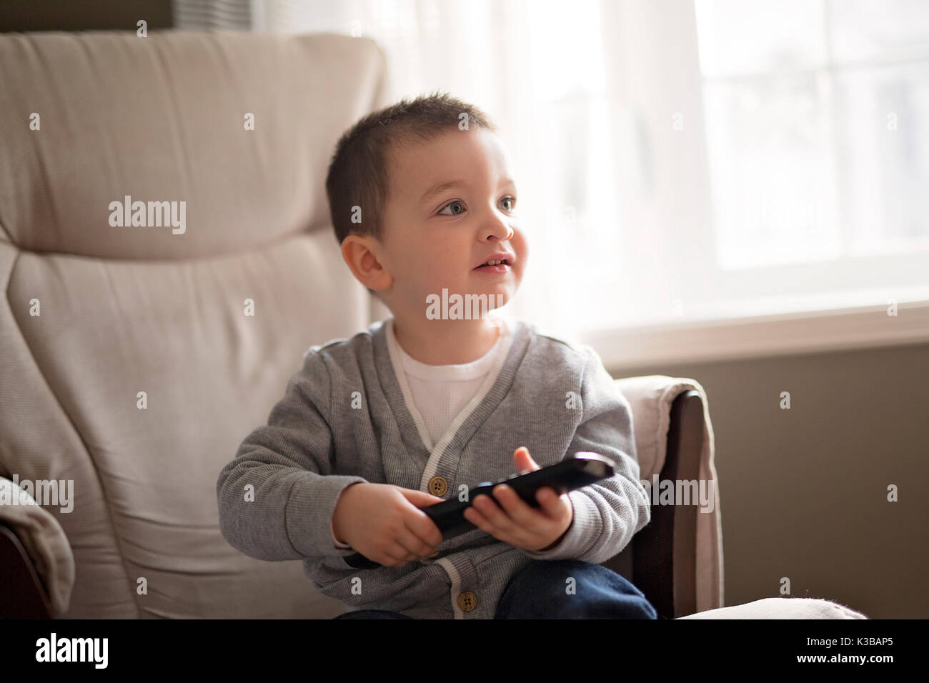 Little boy is watching tv while sitting on a couch Stock Photo - Alamy