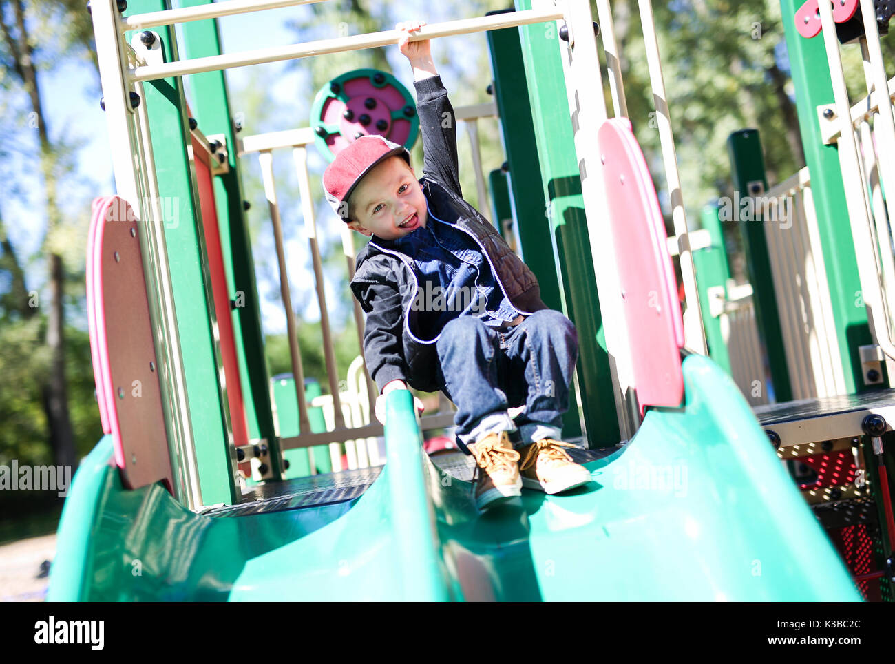 Happy kid having fun playing in slider Stock Photo - Alamy
