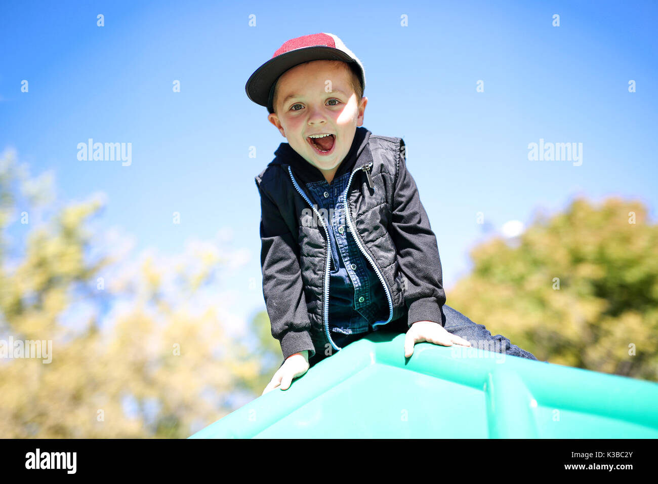 Happy kid having fun playing in slider Stock Photo - Alamy
