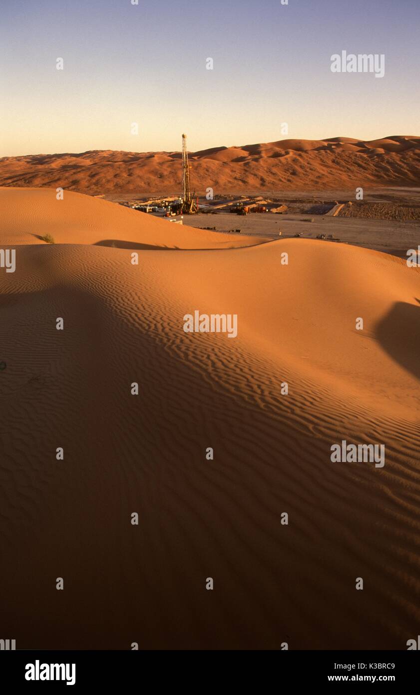 An oil rig searching for oil amongst the sand dunes that will feed into ...